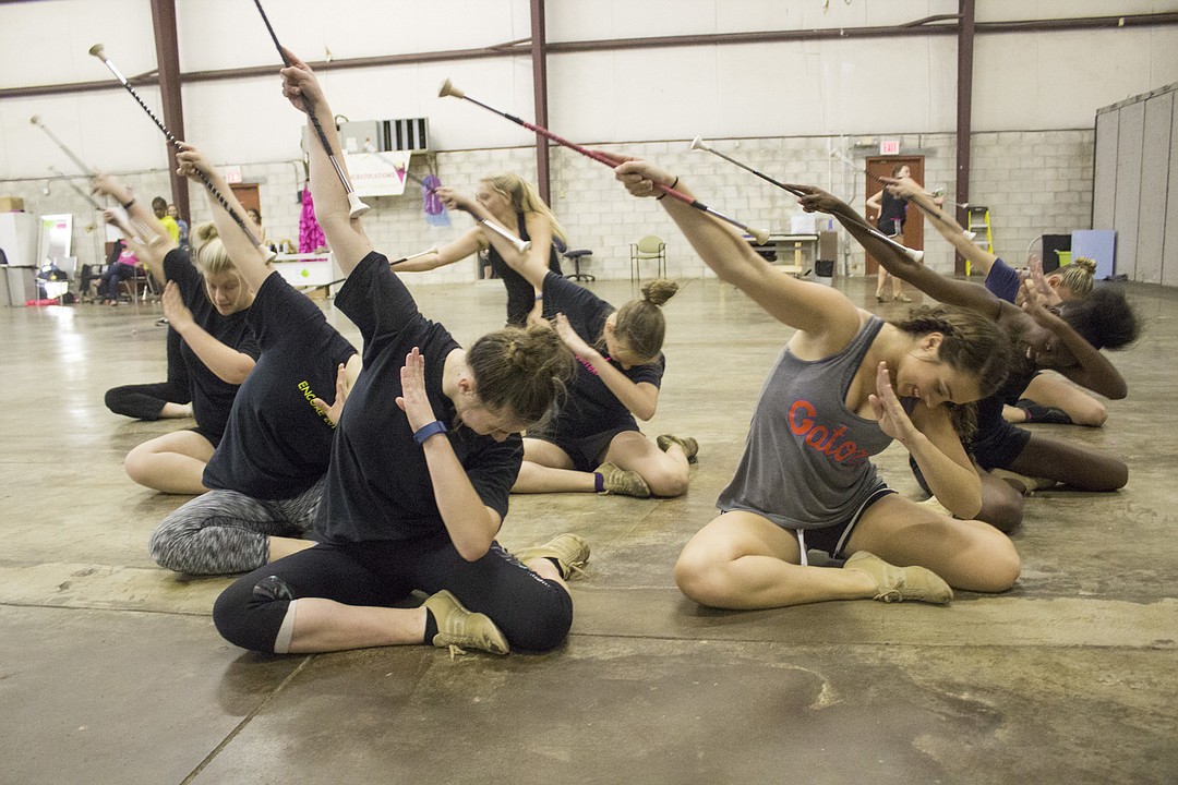 Four princesses and two queens practice baton twirling in a warehouse ...